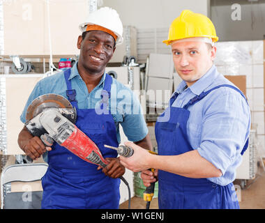 Confident male contractors working with handheld power tools in ...
