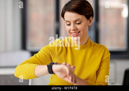 happy businesswoman using smart watch at office Stock Photo - Alamy