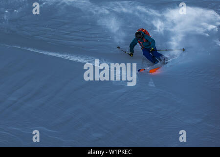 Young male skier riding apart the slopes through the deep powder snow ...