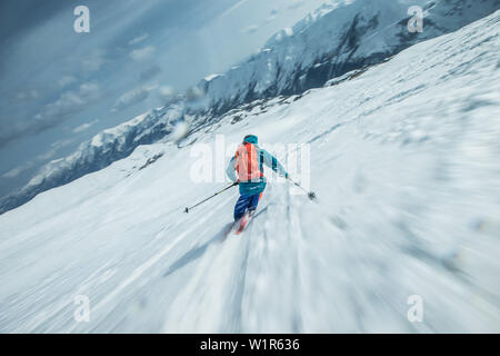Young male skier riding apart the slopes through the deep powder snow ...