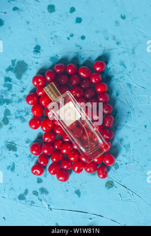 Pile of ripe cherries and glass bottle on blue background. Fresh ...