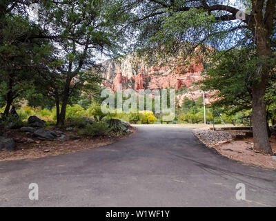 background of a red rock with trees under the blue sky with some clouds ...