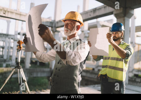 Engineer and building site manager dealing with blueprints and plans ...