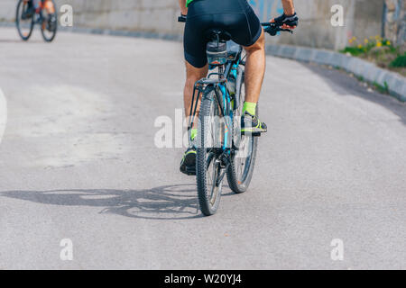Athlete biker rides his bike uphill, wearing professional biking ...
