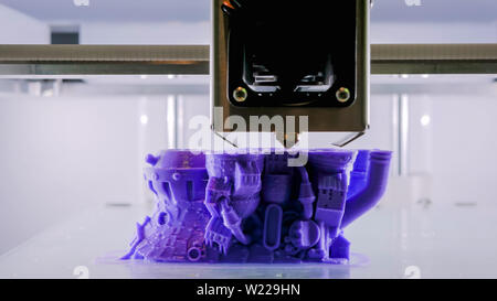 Print head of 3D printer machine printing blue plastic model - close up ...