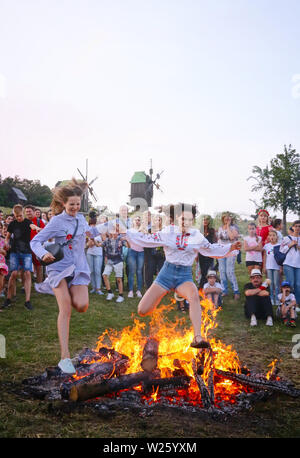 KYIV, UKRAINE - JULY 6, 2018: Young people jump over the flames of ...
