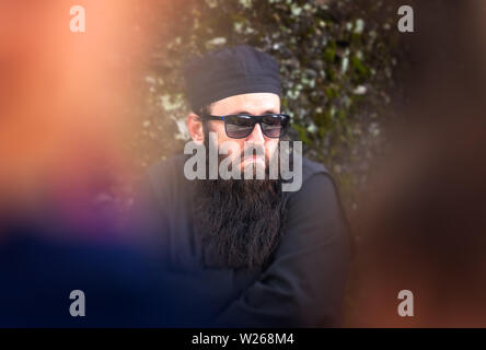 An Orthodox Christian priest with a long white beard sits reading a ...