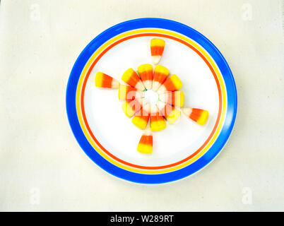 Pieces of Halloween candy corn arranged in a circle on a color ...