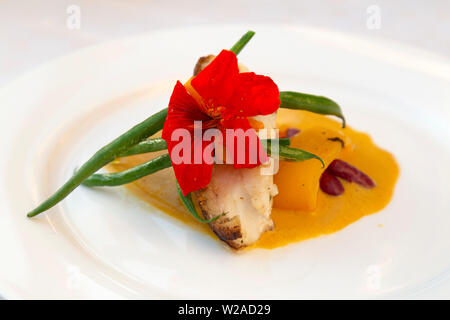 Monkfish is served with vegetables, sauce and an edible flower Stock ...