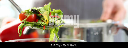 Closeup of male chef putting chopped leek in utensil on burner in ...