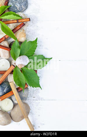 Composition of spa pebbles, candles and bamboo leaf on grey background ...