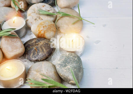 Composition of spa pebbles, candles and bamboo leaf on grey background ...
