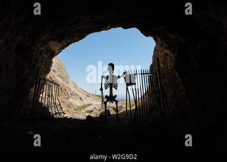 Skeleton silhouette in the mouth of a gated mine stay out stay alive ...