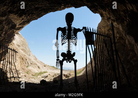 Skeleton silhouette in the mouth of a gated mine stay out stay alive ...