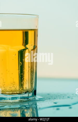 Bubbling yellow fizzy soda drink in glass, close up with selective ...