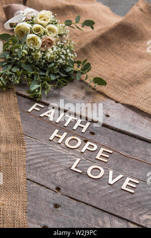 Rustic background with bouquets and burlap with the words Faith, Hope ...