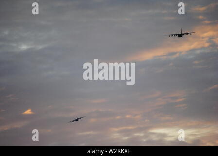 A pair of C 130 Hercules transport aircraft flying in to sun set clouds ...