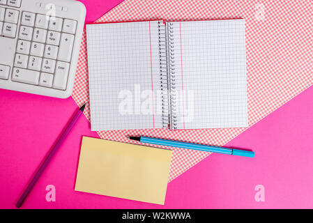 Writing equipments and computer stuffs placed above colored plain table ...