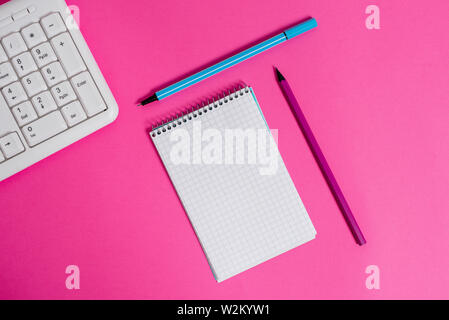 Writing equipments and computer stuffs placed above colored plain table ...