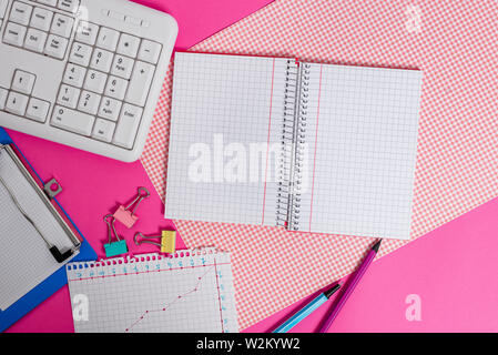 Writing equipments and computer stuffs placed above colored plain table ...