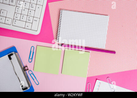 Writing equipments and computer stuffs placed above colored plain table ...