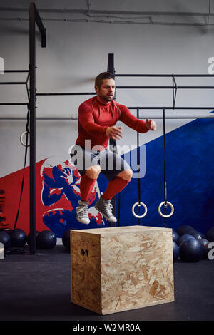Strong man doing a box jump exercise at workout gym. Male athlete using ...