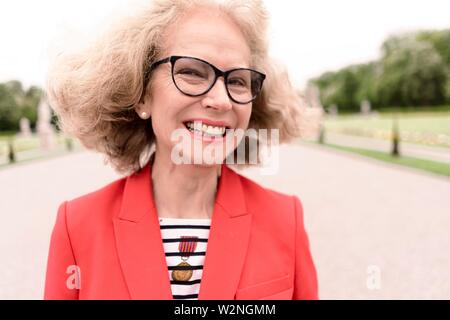 Portrait of stylish 67 year old woman in a bright red coat, with ...