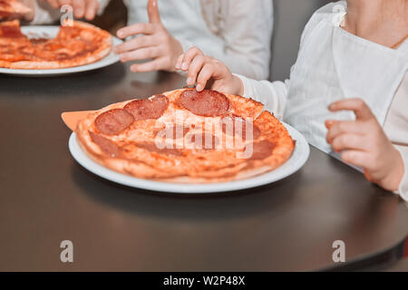 close up. small participants of the master class eat pizza . cooking ...