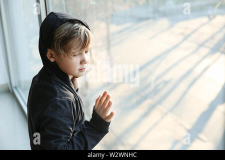 Homeless little boy near window indoors, view through glass Stock Photo ...