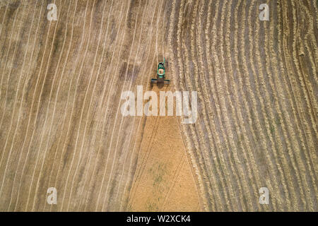 Aerial shot of a combine harvesting triangle peice of crop field on a ...