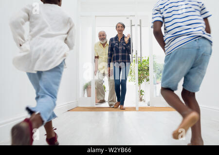 Children running towards an old couple by the door Stock Photo - Alamy