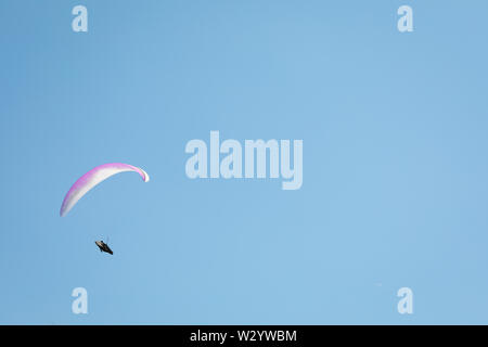 Skydiver with a white-pink parachute flies across the blue sky Stock ...