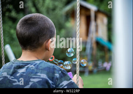 Boy blowing bubbles at yard Stock Photo - Alamy