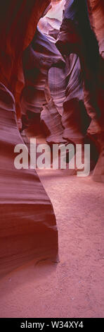 A narrow crack in a rock formation reveals a glimpse of the landscape ...