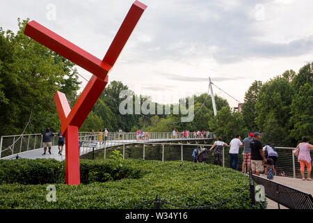 Visitors to Falls Park linger on Liberty Bridge overlooking the Reedy River waterfalls in ...