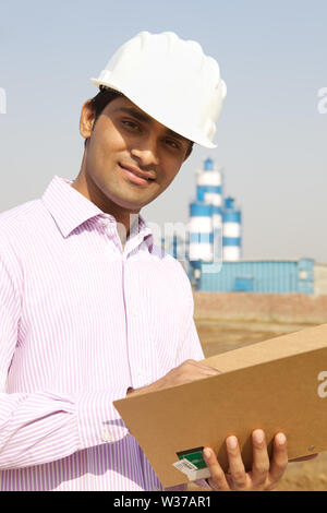 Engineer checking building documentation on clipboard at construction ...