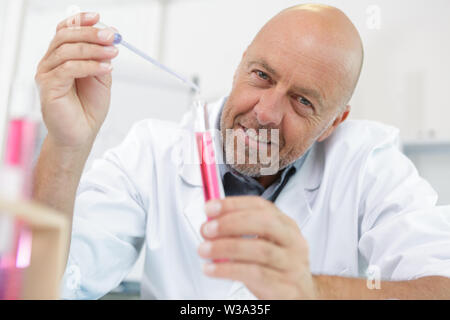 Elderly man scientist doing research analysing liquid in tube at modern ...