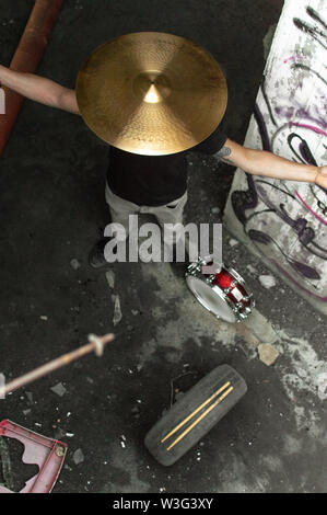 Drummer in grunge place with a cymbal of a drum in his head and snare ...