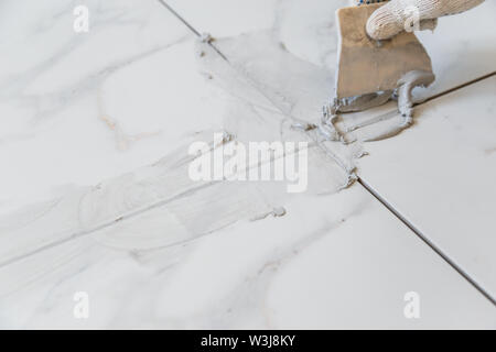 Grouting tiles seams with a rubber trowel Stock Photo - Alamy