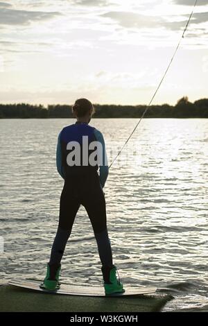 Wakeboarder making tricks. Low angle shot of man wakeboarding on a lake ...