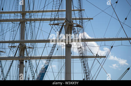 Detail of main mast of tall ship with two seamen on top yard securing ...