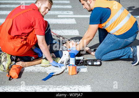 Ambluence worker applying emergency care to the injured bleeding man ...