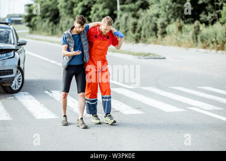Medic in uniform helping injured man to walk, applying first aid after ...
