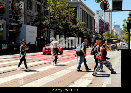 Pedestrians using a crosswalk to walk across Market Street in downtown ...