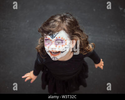 Portrait of a girl with a painted mask of a dead person on her face ...