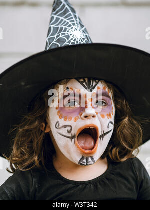 Portrait of a girl with a painted mask of a dead person on her face ...