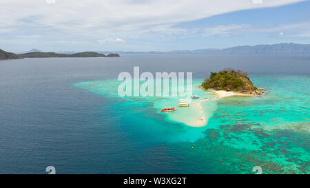 Island with a sand spit and coral reefs. Clear transparent sea near the ...
