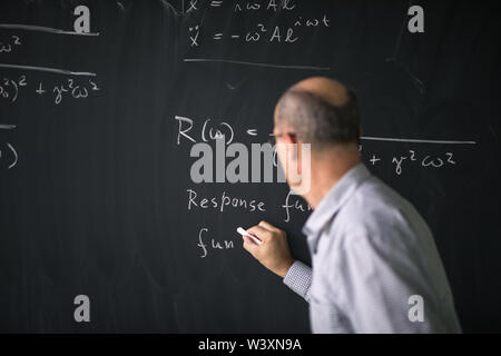 Math teacher drawing fuction graph on a blackboard during mathclass ...