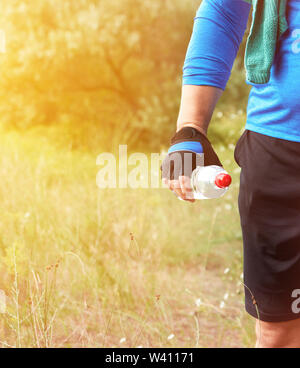 A hand in a green plastic glove holding a scalpel covered in blood ...