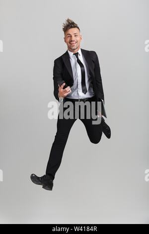 Handsome bearded businessman with laptop jumping near grey wall Stock ...